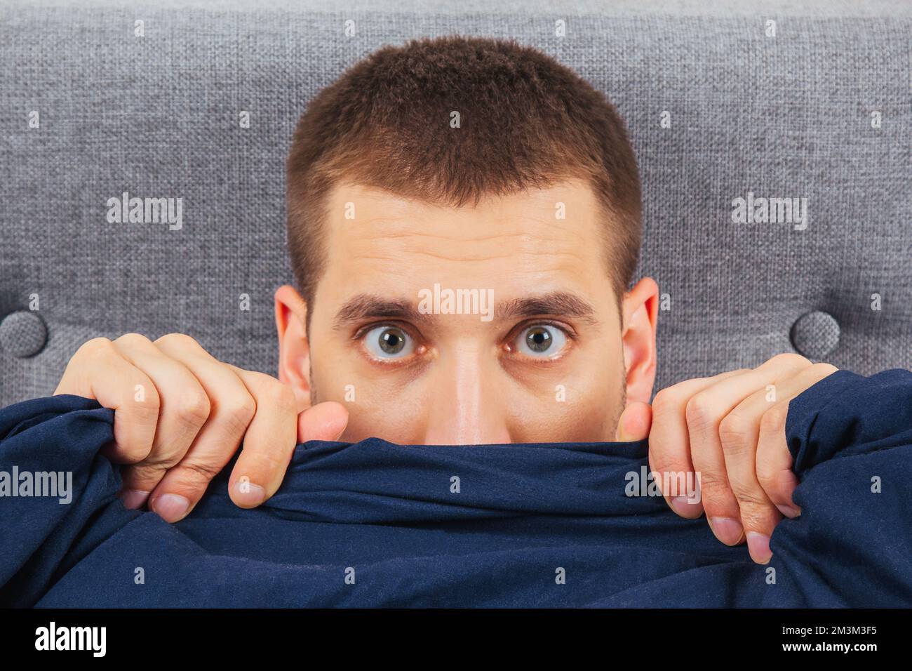 Looking straight into the frame. A handsome young guy hiding behind a ...