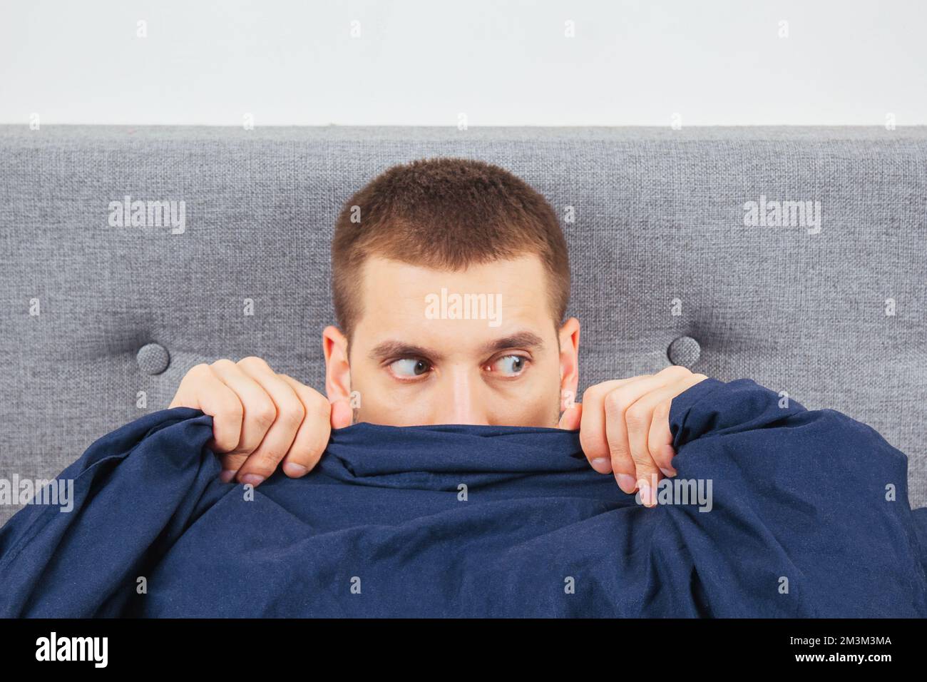 Look to the right. A handsome young guy hiding behind a blanket looks ...