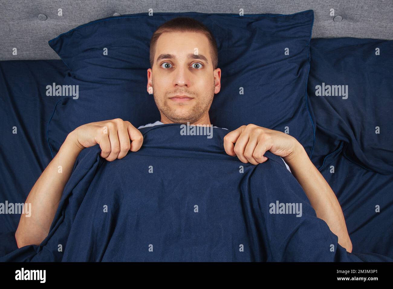 Looking straight into the frame. A handsome young guy hiding behind a ...