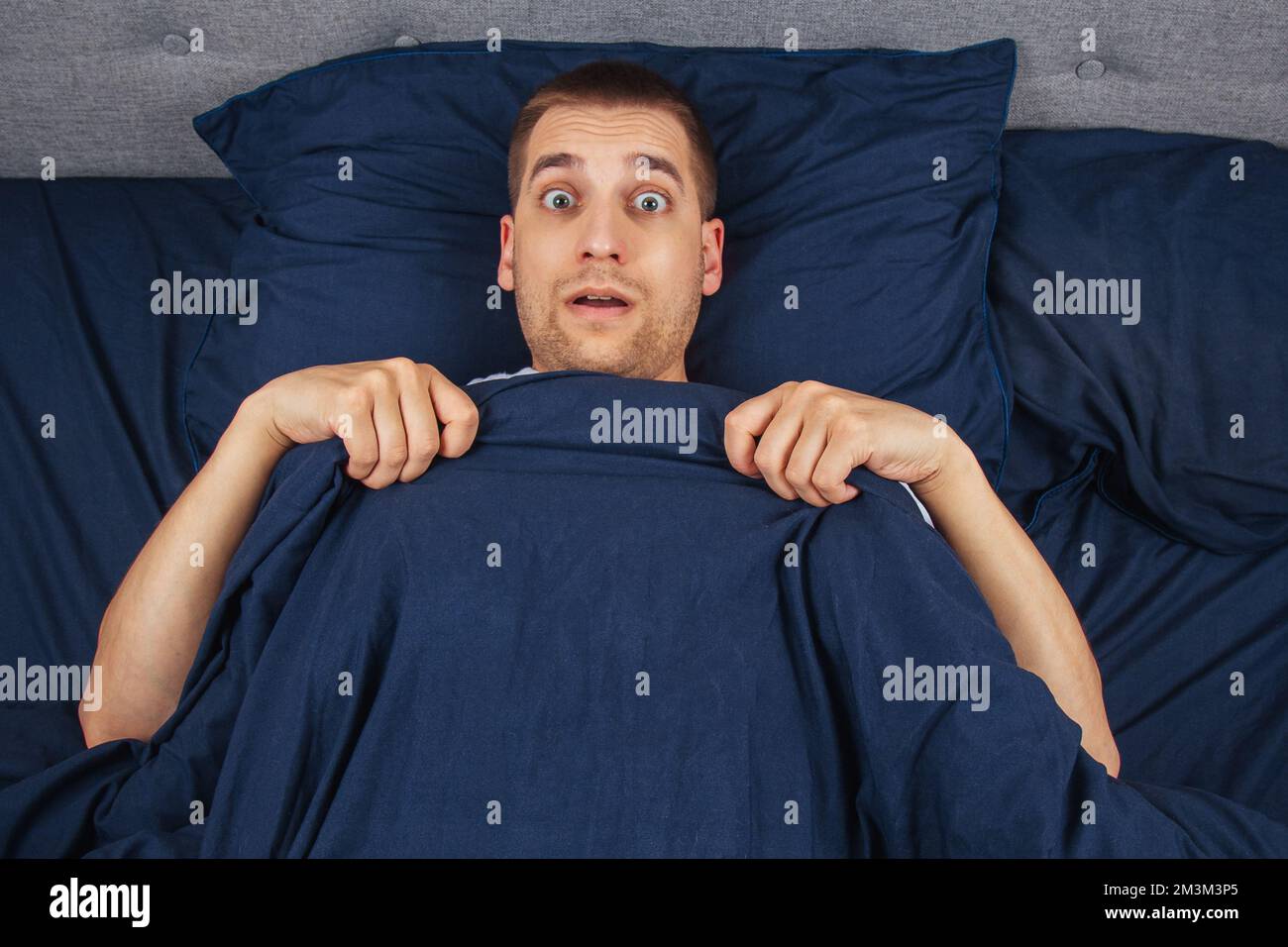 Looking straight into the frame. A handsome young guy hiding behind a ...