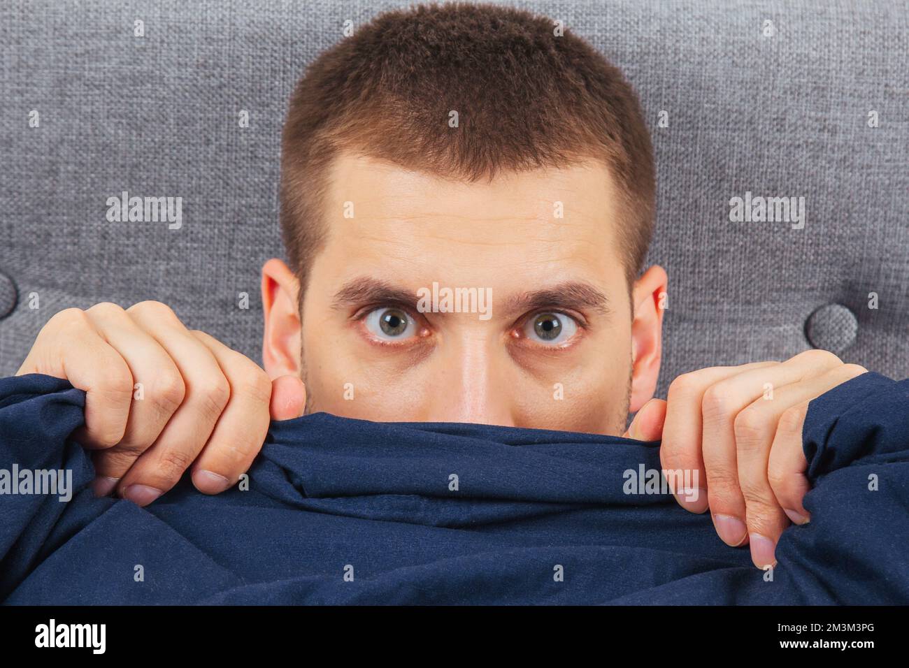 Looking straight into the frame. A handsome young guy hiding behind a ...