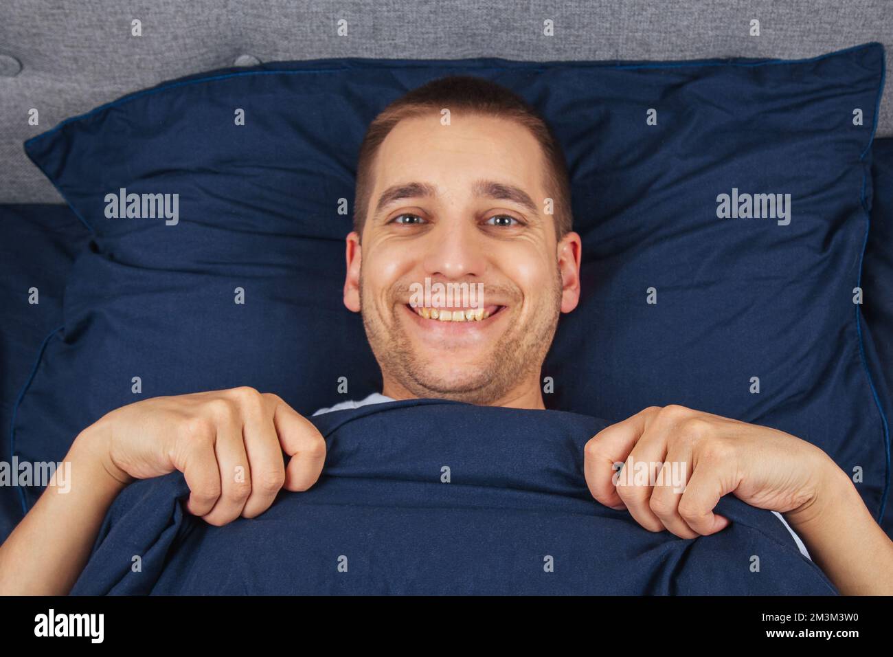 Looking straight into the frame. A handsome young guy hiding behind a ...