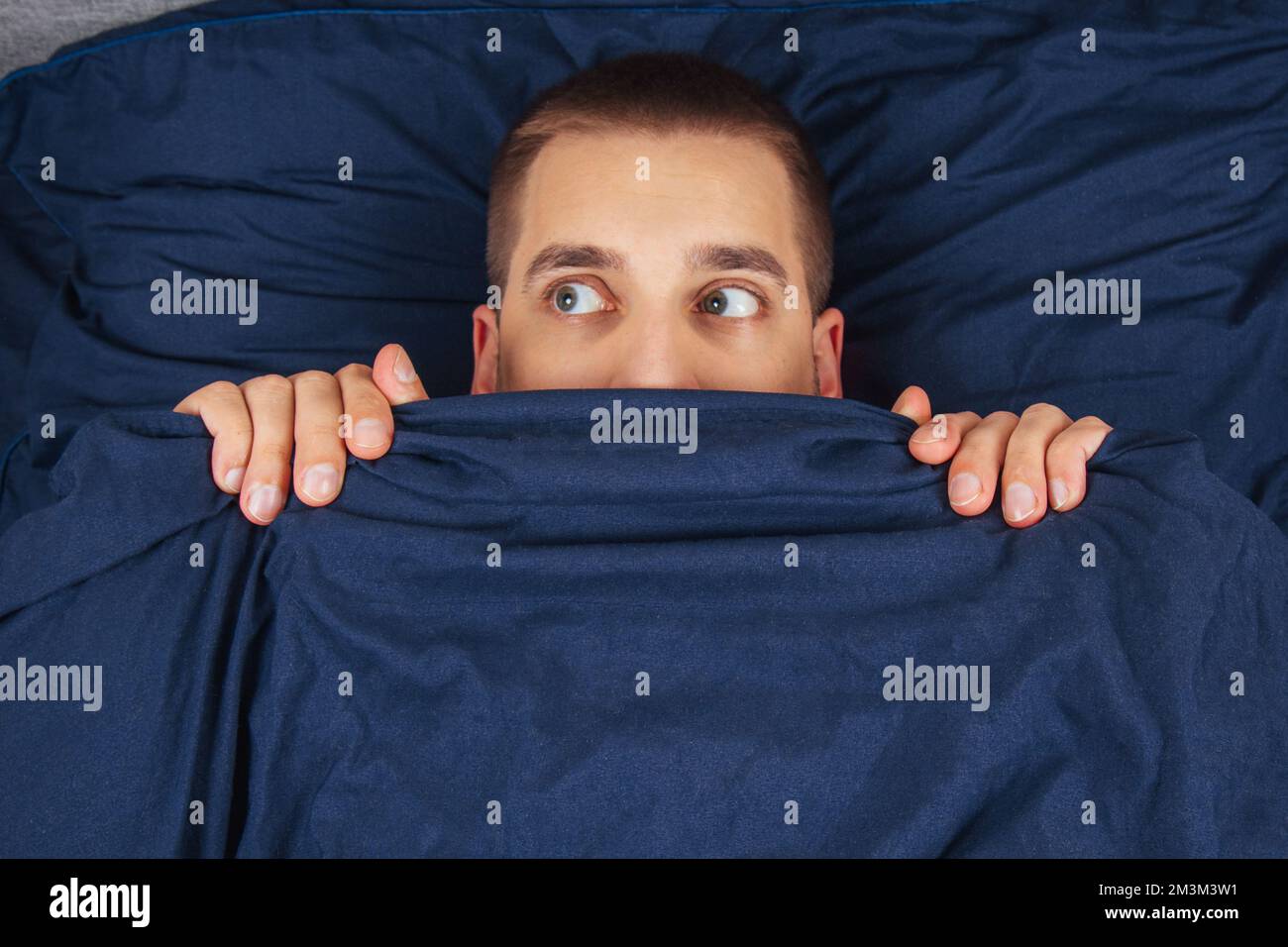 Look to the left. A handsome young guy hiding behind a blanket looks to ...