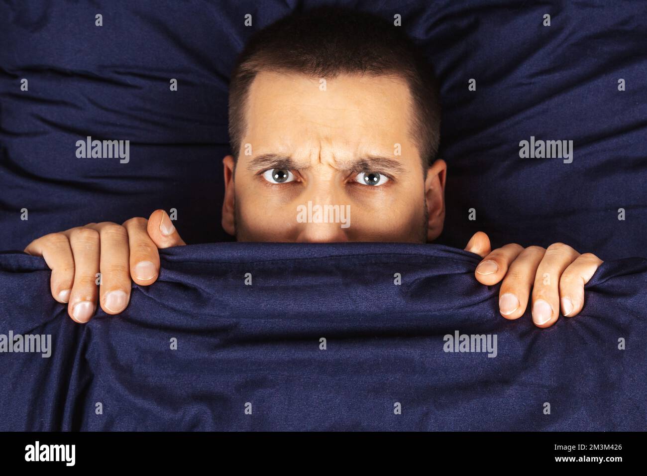 Looking straight into the frame. A handsome young guy hiding behind a ...
