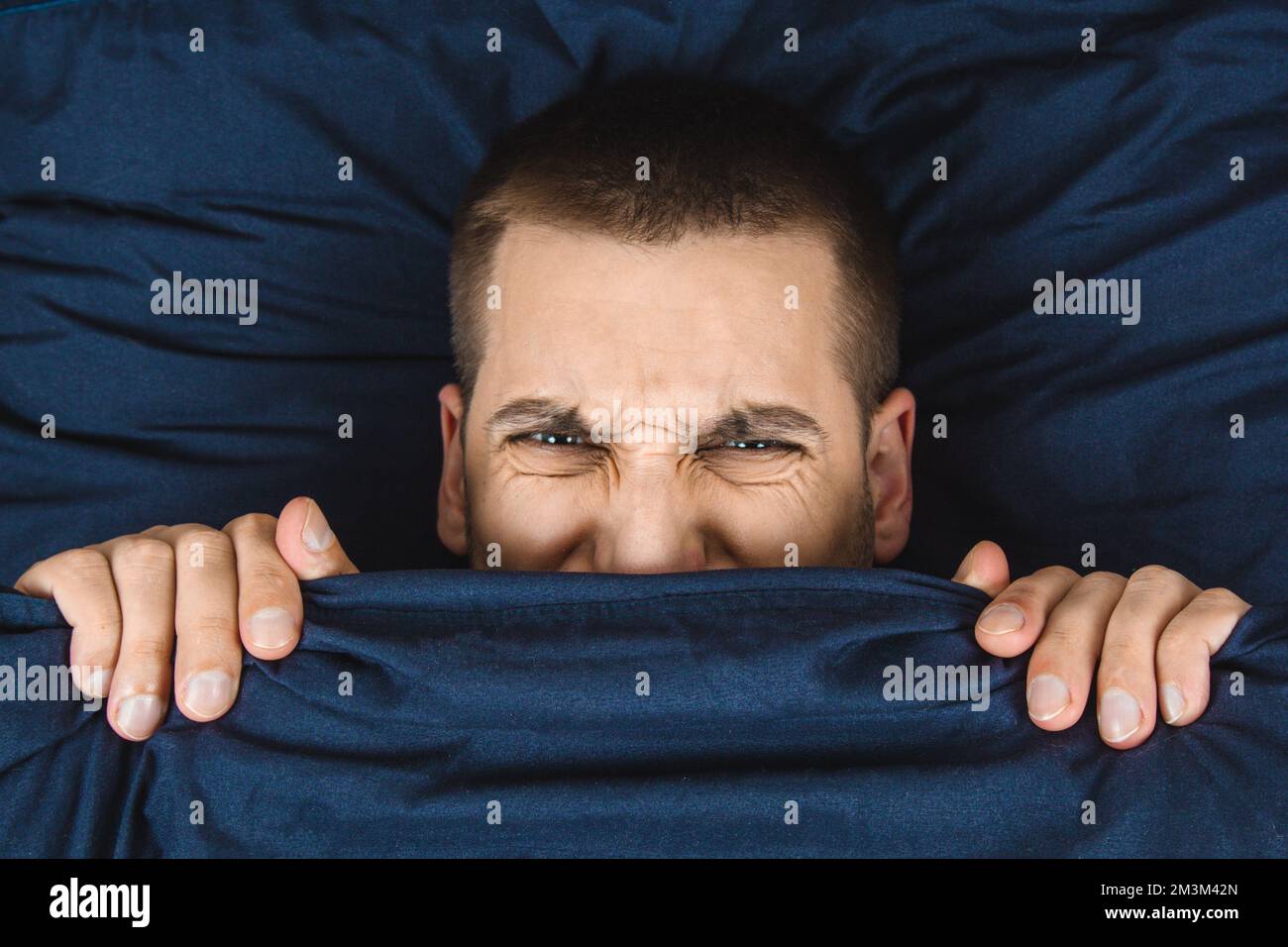 Looking straight into the frame. A handsome young guy hiding behind a ...