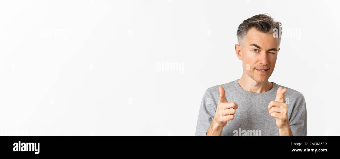 Close-up of handsome cheeky man with gray hair, winking and pointing ...