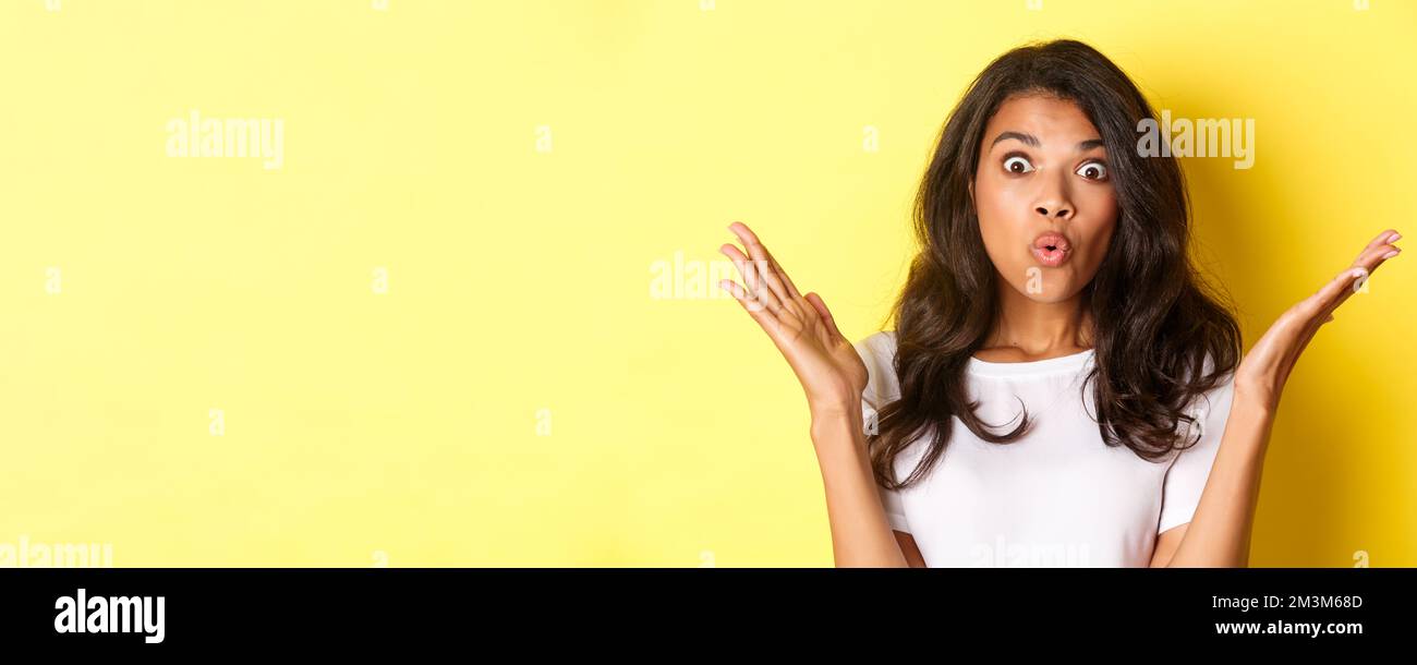 Close-up of surprised african-american girl, raising hands up and ...
