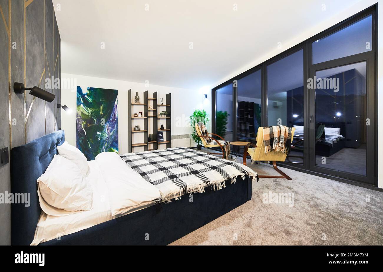 Chalet room with reflection in large panoramic window at twilight. Side ...