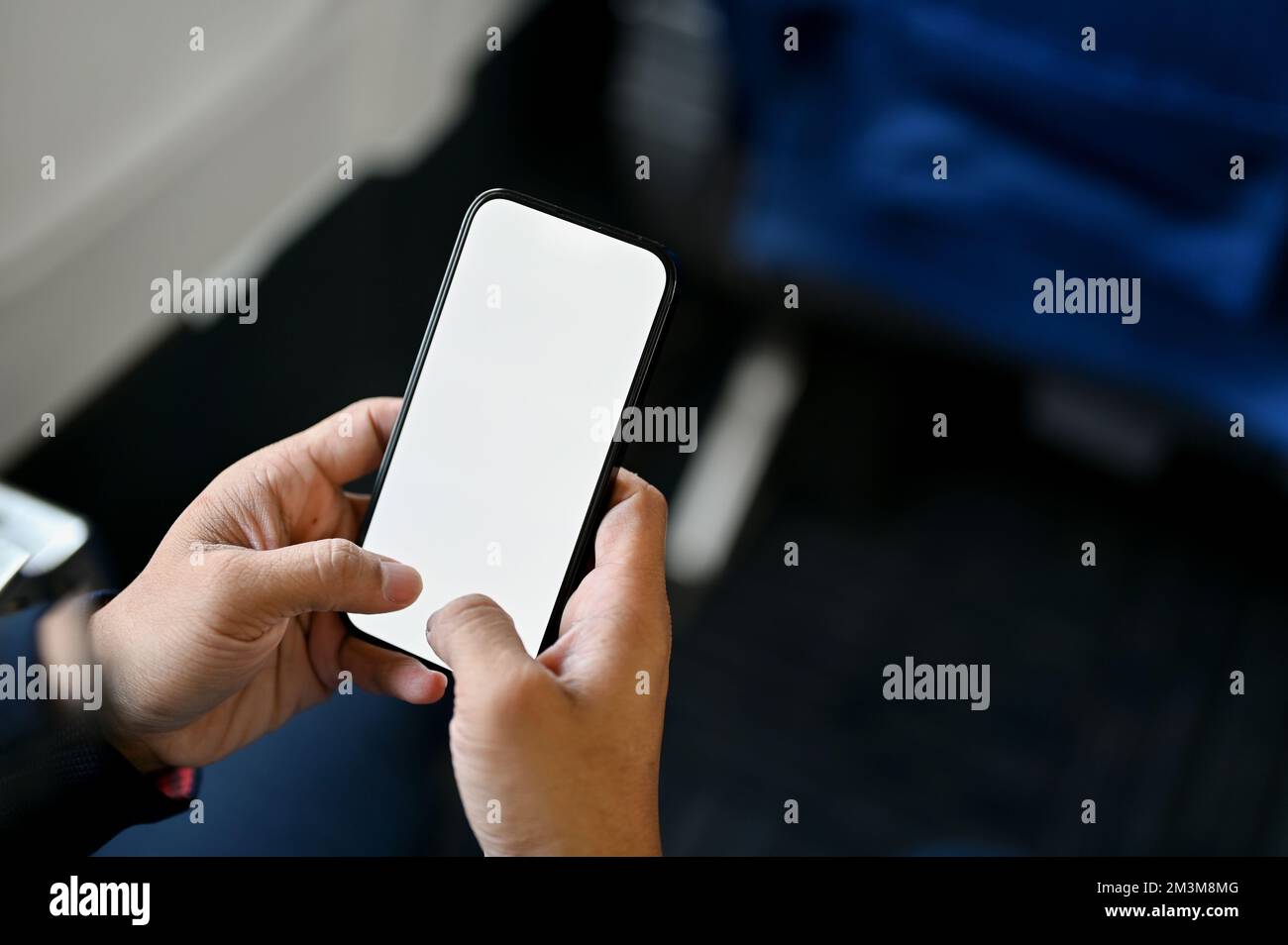 A male passenger using his smartphone, typing on screen, chatting or sending email during the ...