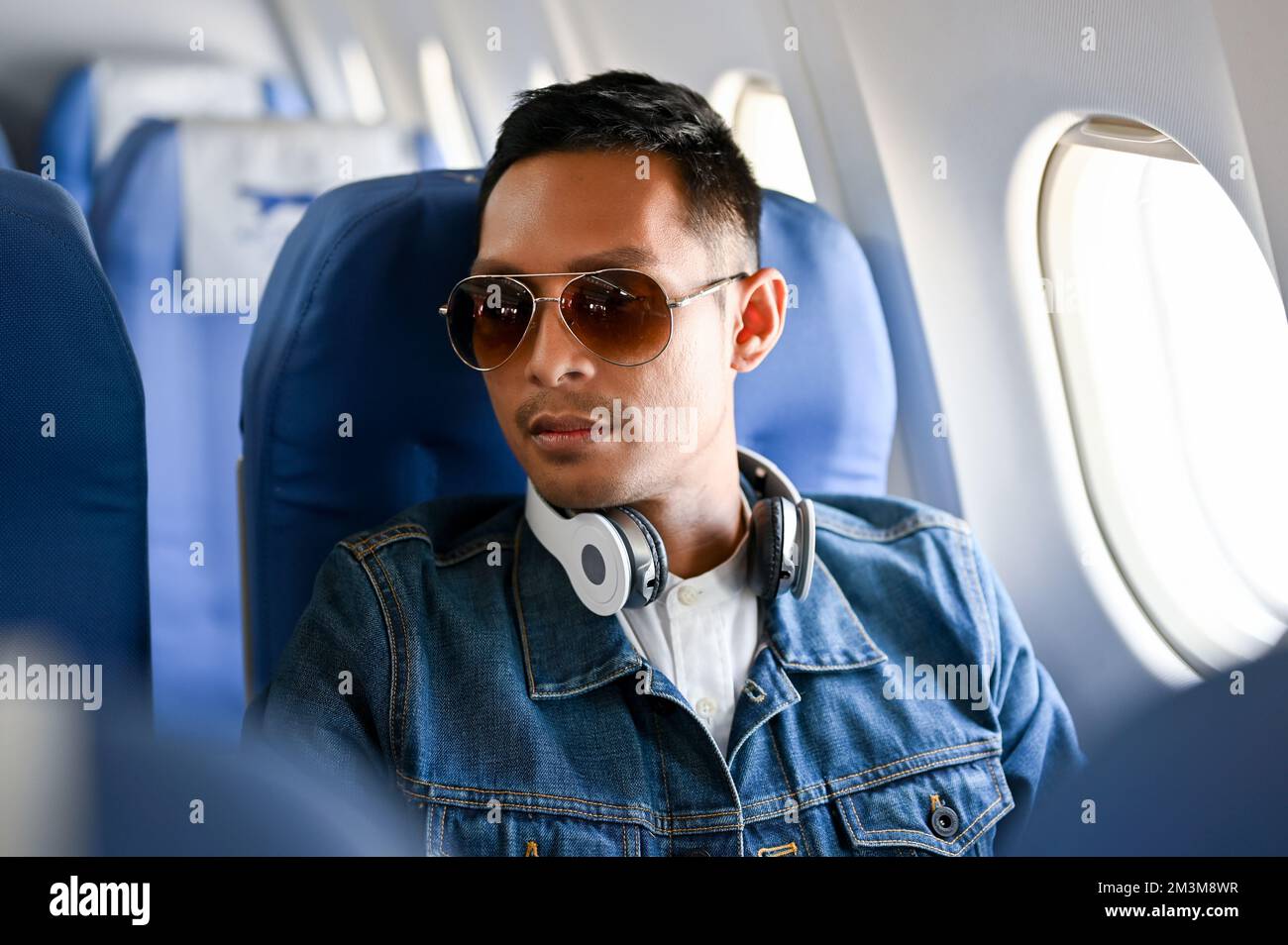 Handsome Adult Asian male tourist wearing sunglasses sits at the window ...