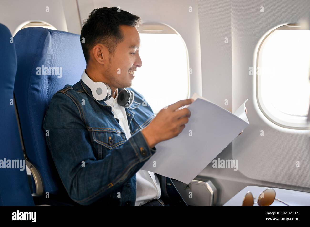 Happy and joyful adult Asian male passenger in the window seat is ...