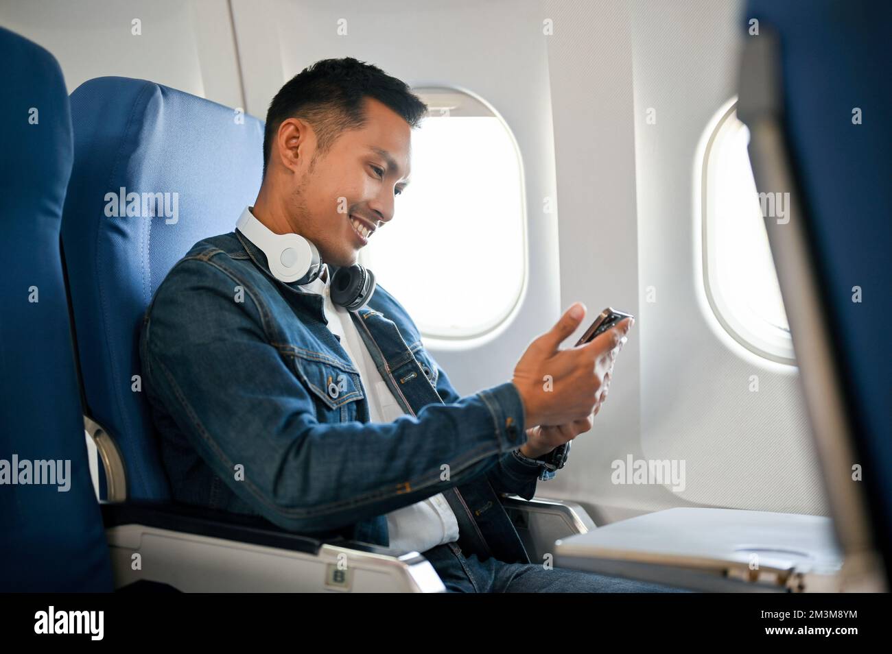 side view, Smart and handsome adult Asian male passenger using his ...