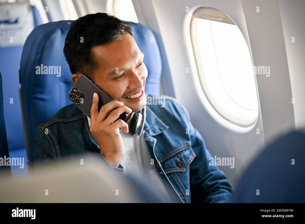 Handsome and happy adult Asian man is on the flight to hometown ...