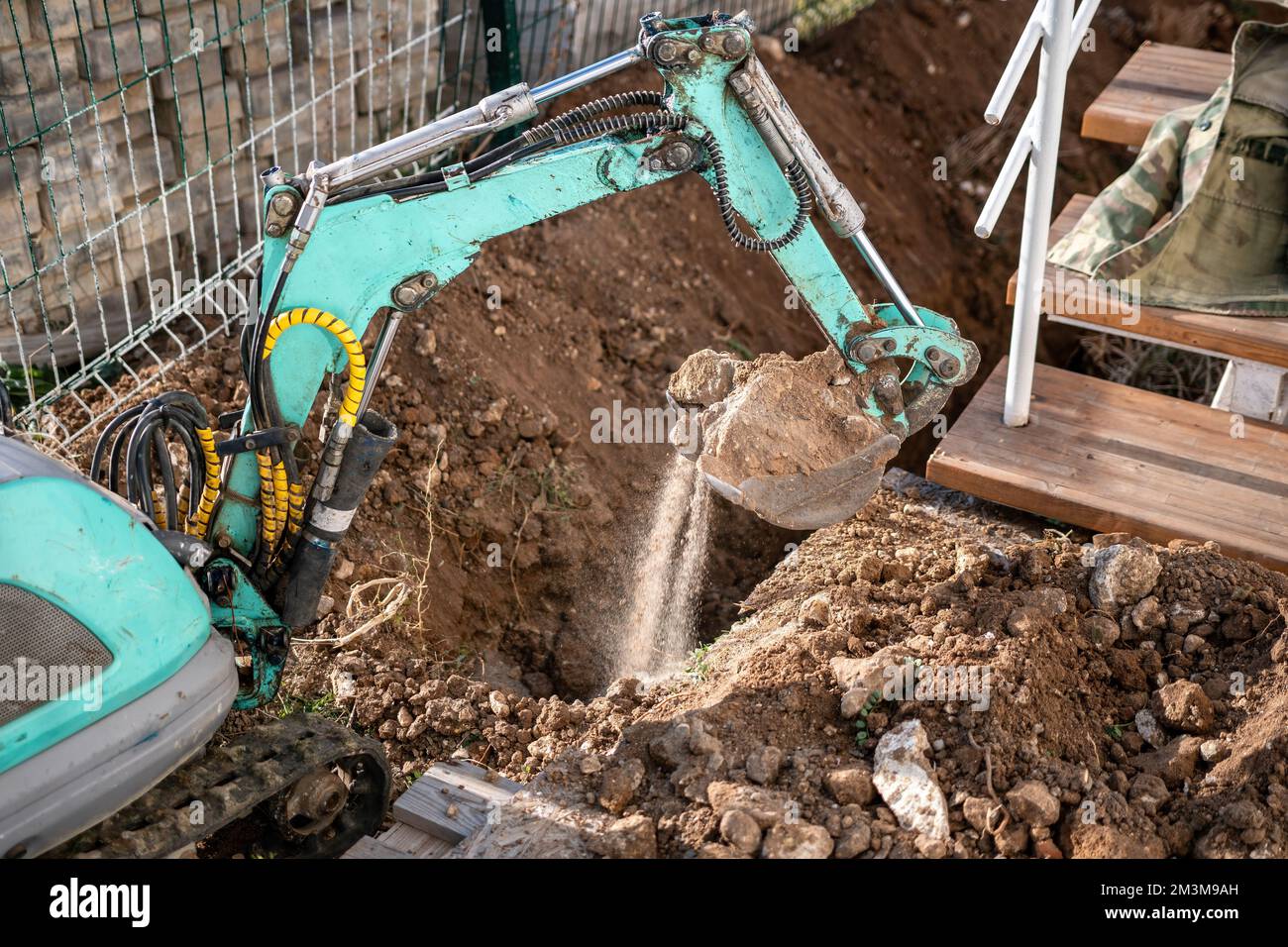 Mini excavator digs a trench to lay pipes. Close up of an excavator ...