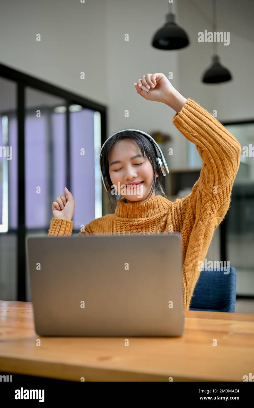 Portrait, Joyful and happy young Asian female in cozy sweater sits at ...