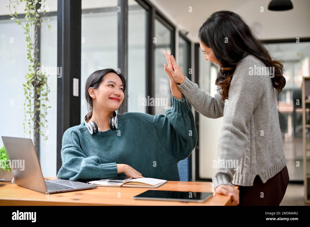 Happy and cheerful Asian businesswoman giving high five to her female ...
