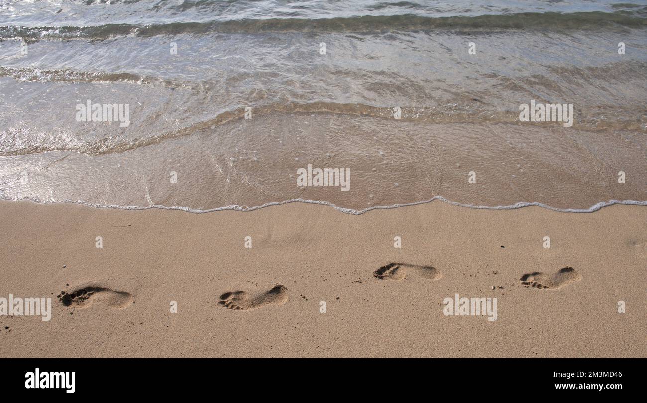 Footprints at golden sand, footsteps. Blue ocean wave on sandy beach ...