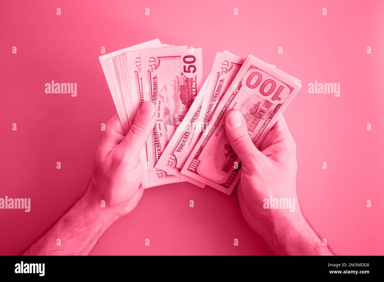 men's hands hold and count 100 and 50 dollar bills on pink background ...