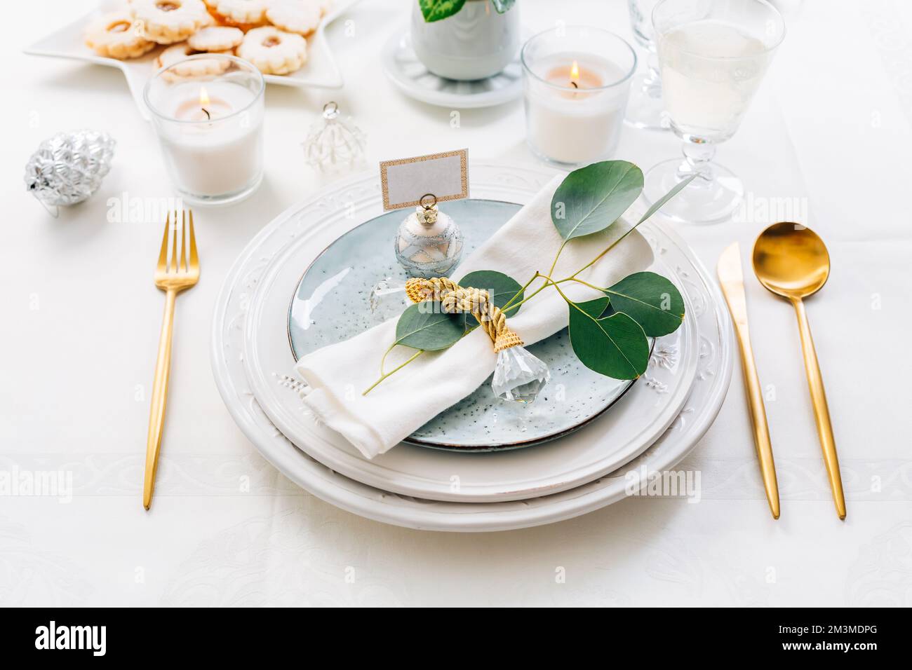 Christmas table setting with eucalyptus, cutlery and candles in white ...