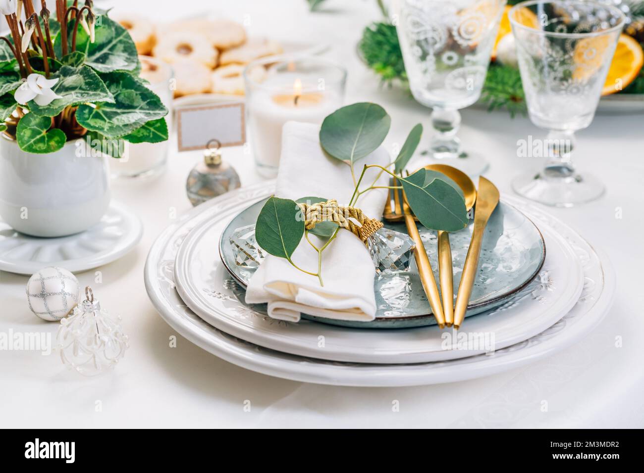 Christmas table setting with eucalyptus, cutlery and potted cyclamen in ...