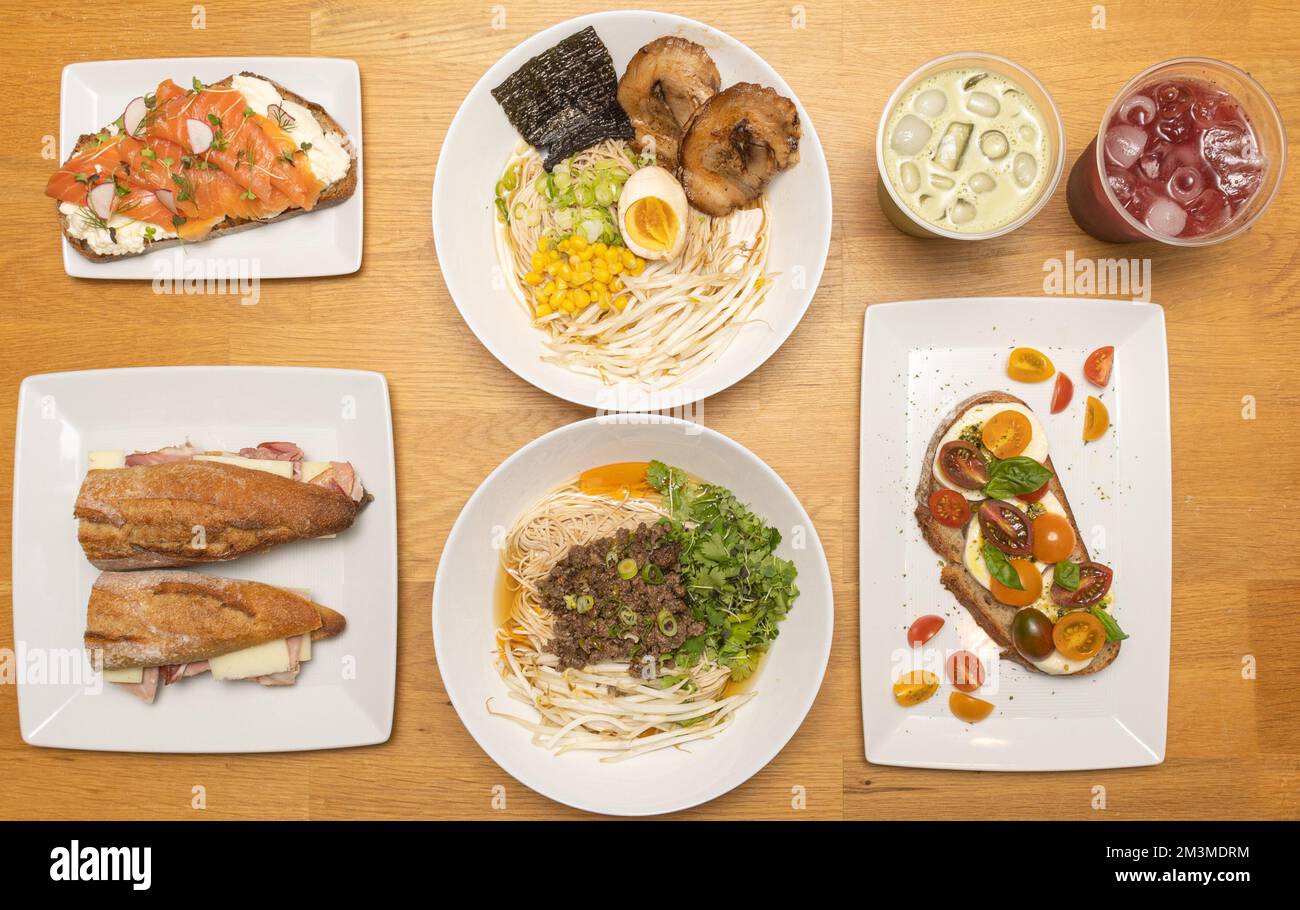 A top view of different meals with ramen, lemonades, and sandwiches on ...