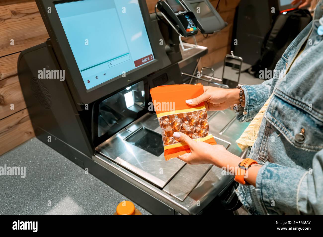 A Girl Customer Scanns And Pays For Goods From A Supermarket In An