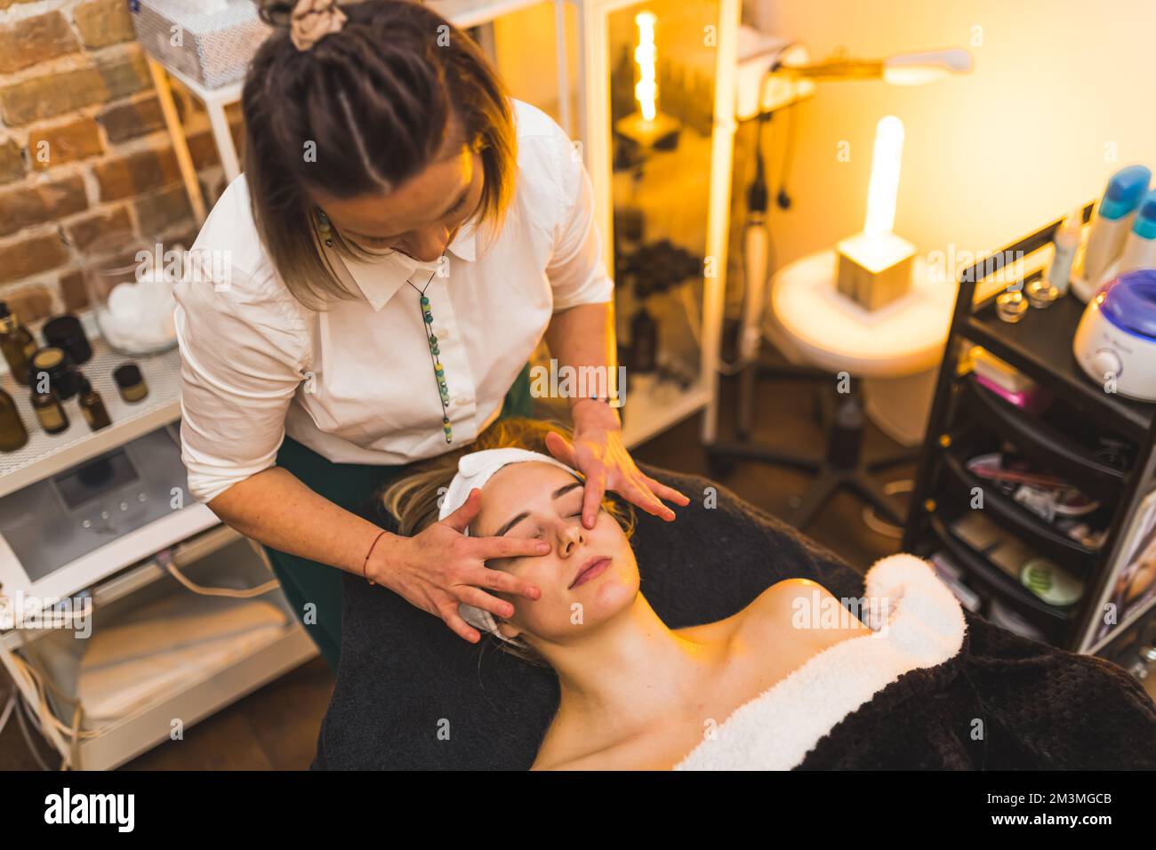 Professional beautician doing a massage on her happy blonde client's ...