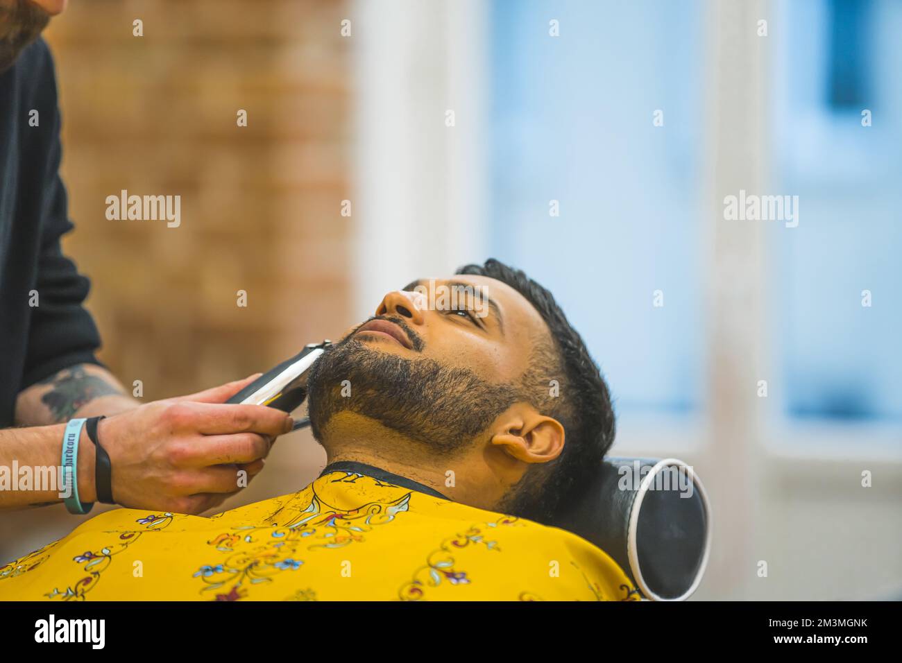 Happy indian client having his beard trimmed by a profssional barber in ...