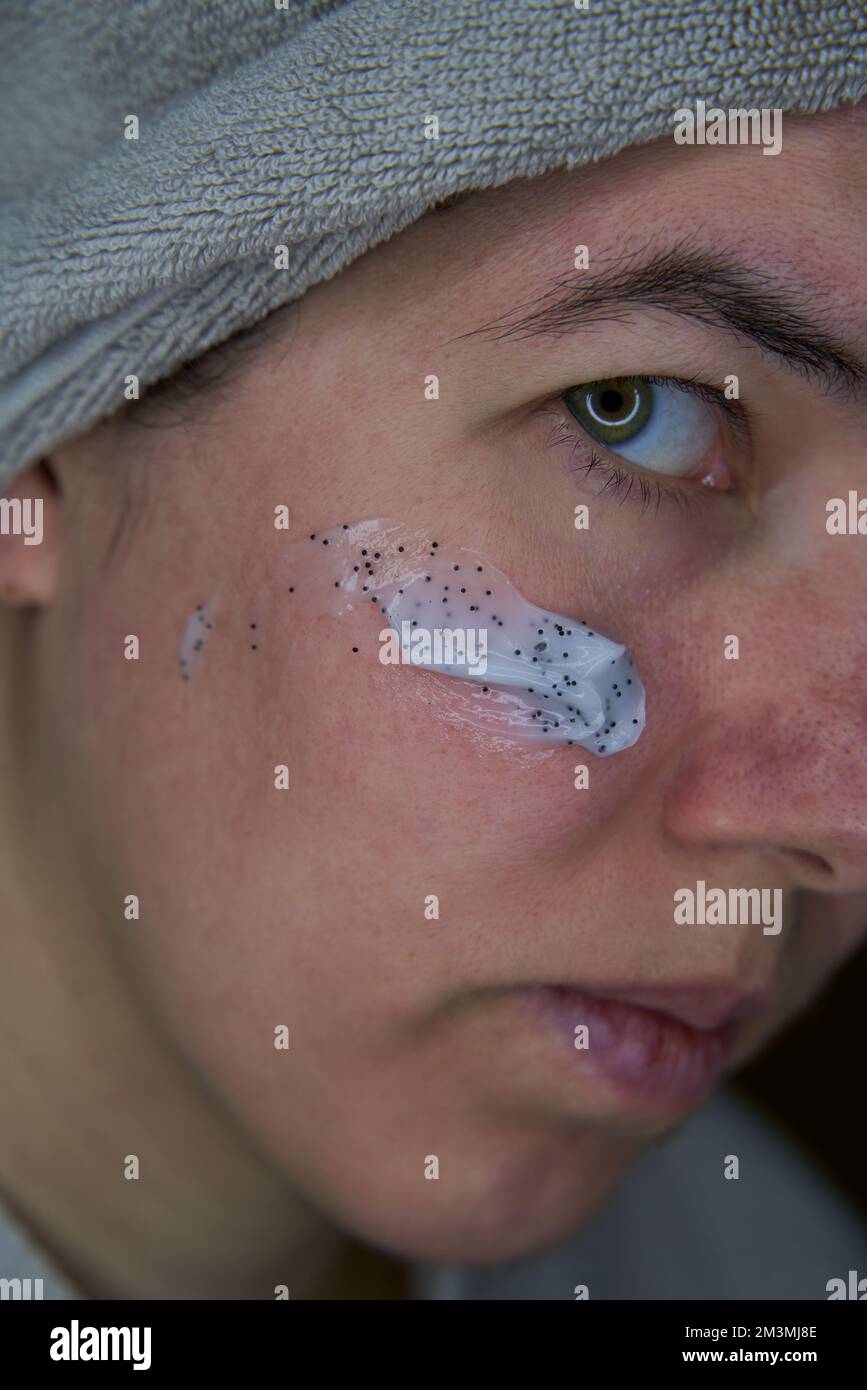 Woman with a towel over your head and smear of scrab on her face. Skin ...