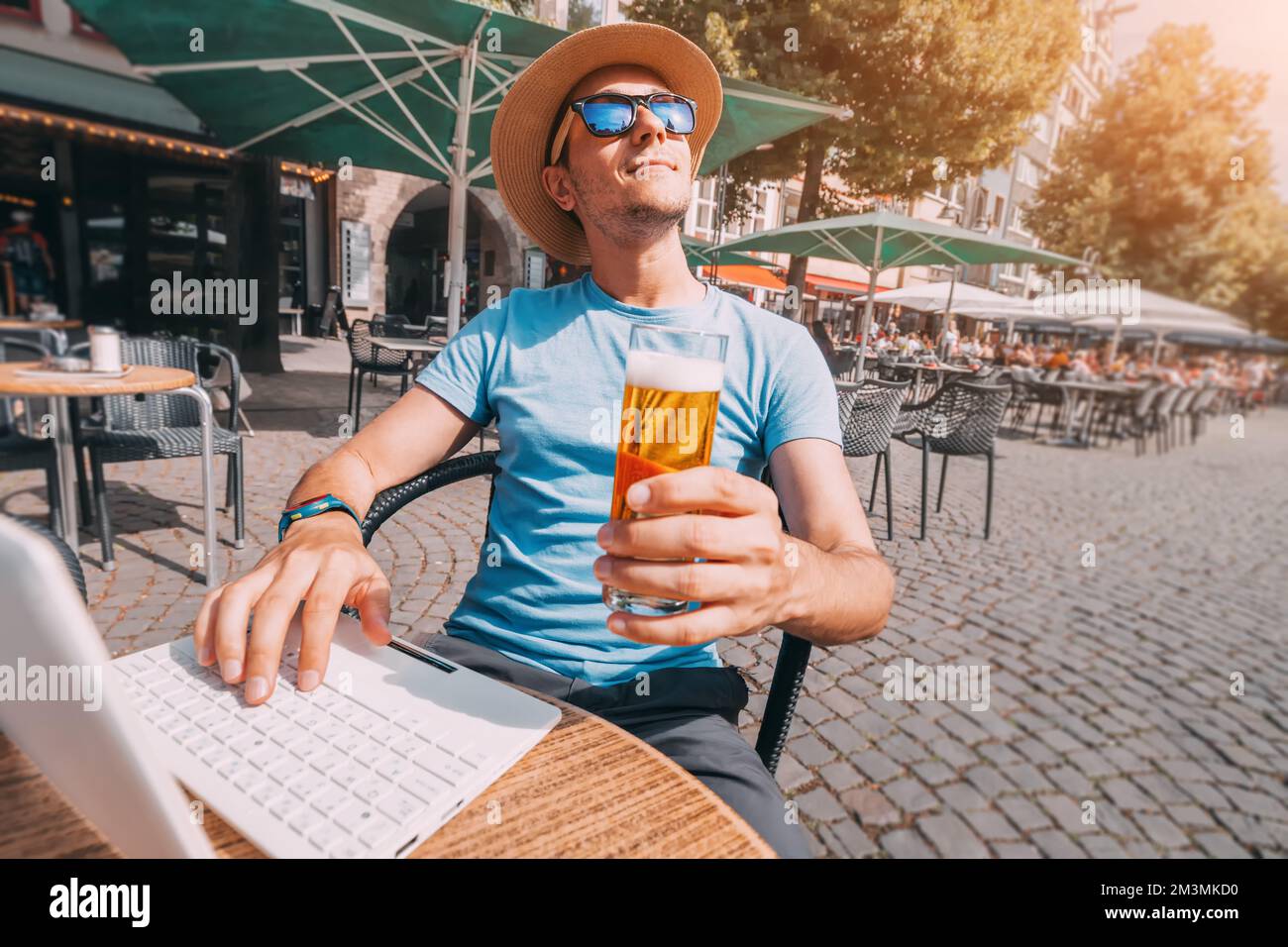 Happy man relaxes and drinks a glass of beer in a pub in the fresh air ...