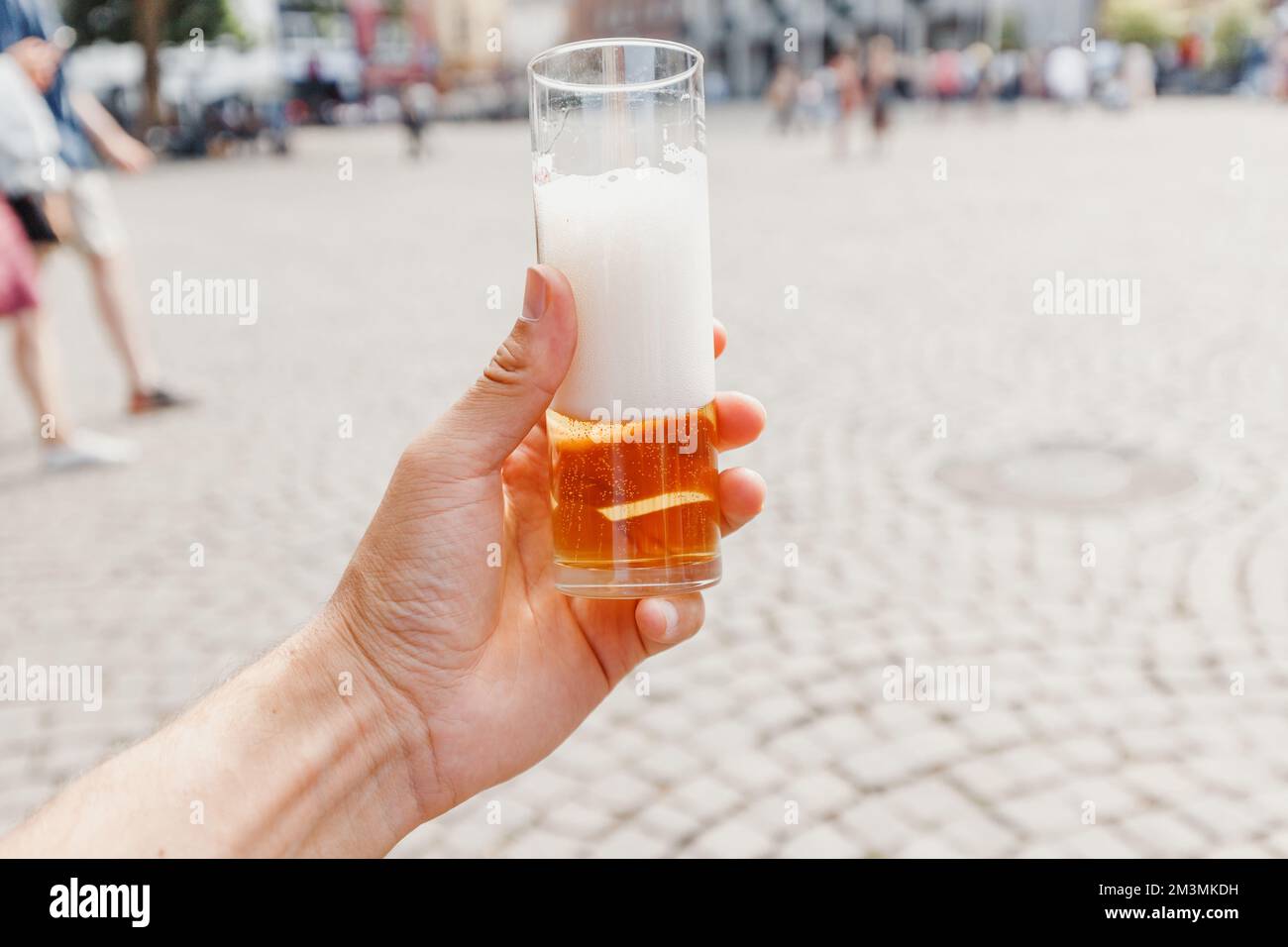 Hand with traditional Cologne kolsch beer in outdoor pub with old town ...