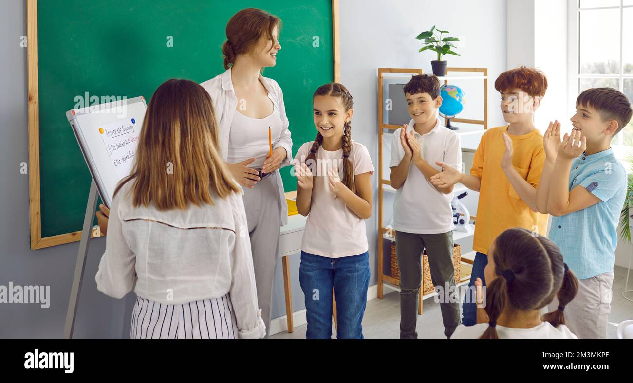 Children teens and teacher elementary school applauding female classmate who wrote correct ...