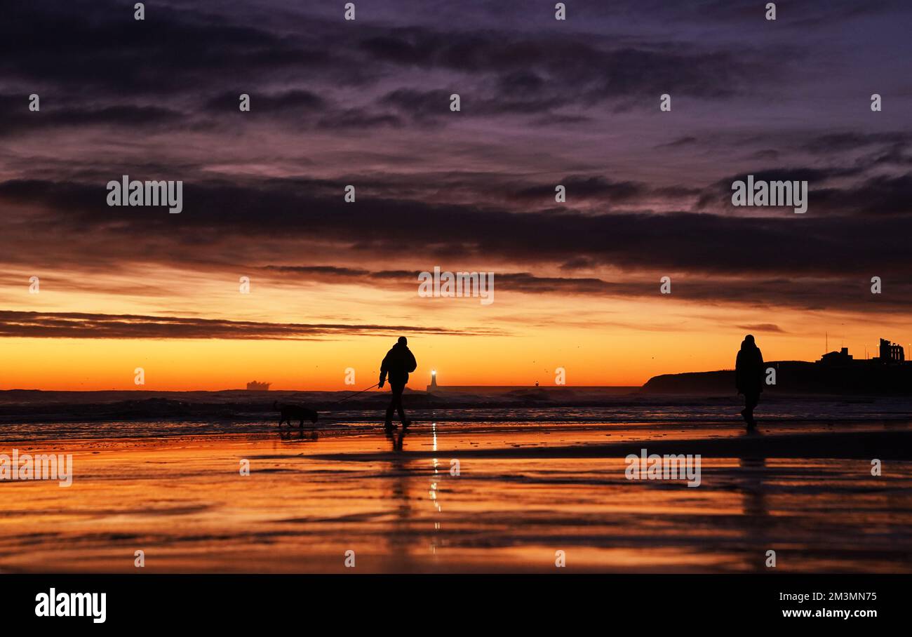 Dog walkers on the beach as the sun rises in Tynemouth on the north east coast. Snow and ice ...