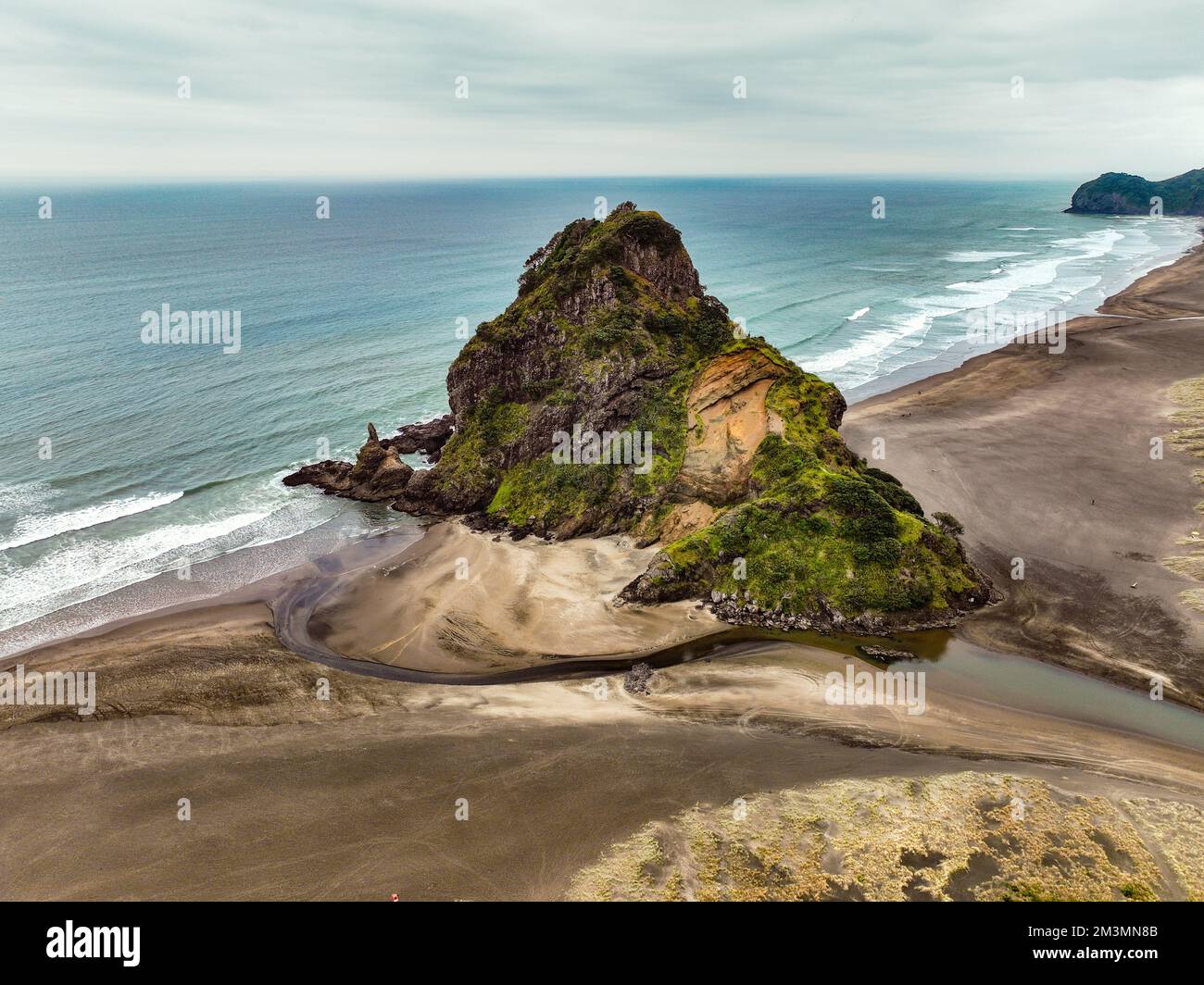 An aerial view of the Lion Rock on Piha Beach with a cloudy sky in the ...