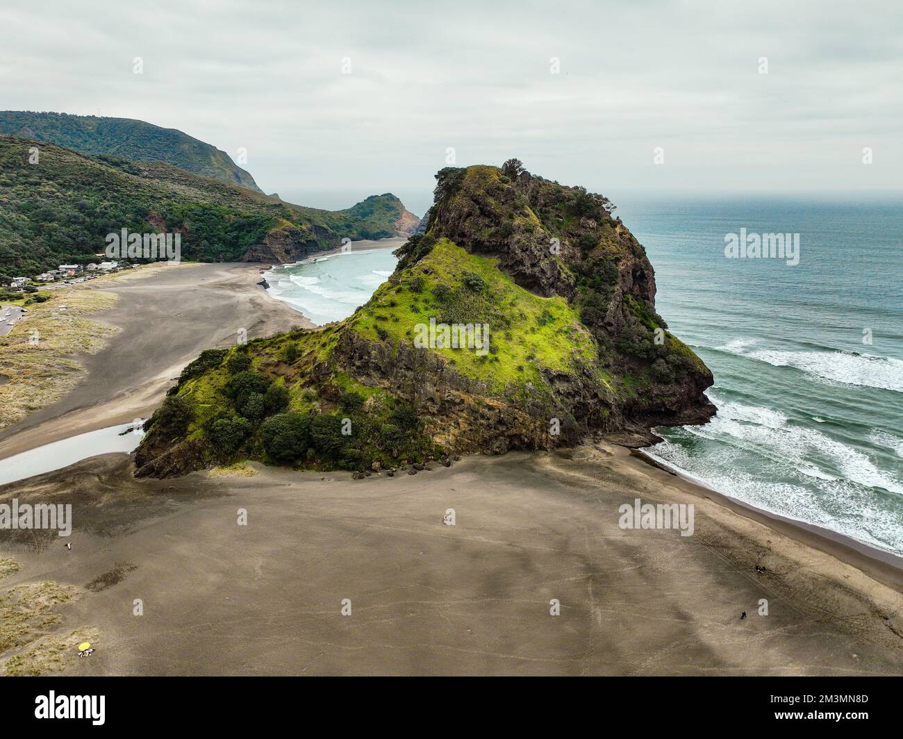 An aerial view of the Lion Rock on Piha Beach with a cloudy sky in the ...