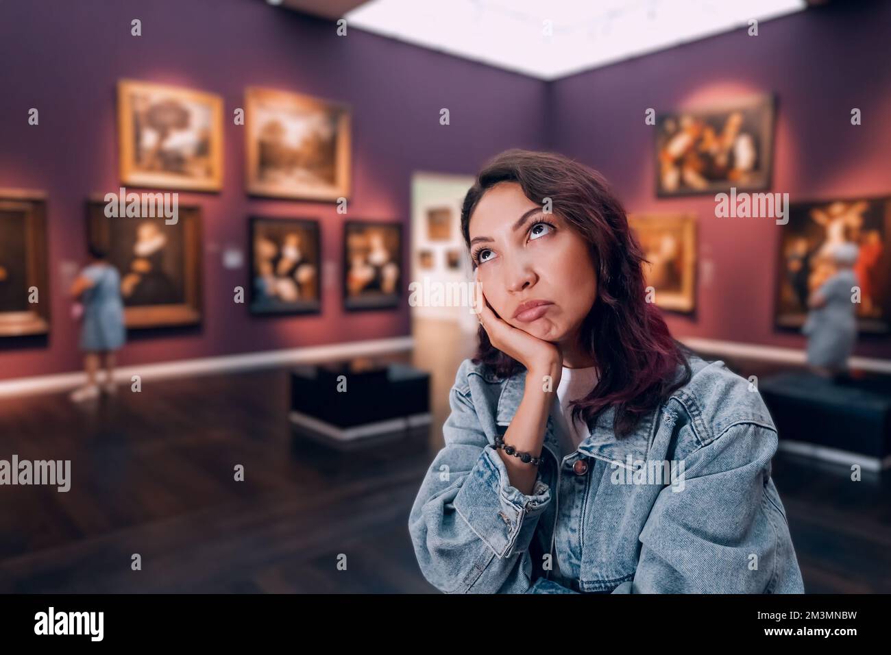 a bored girl visitor or student in an art gallery or museum looks at ...