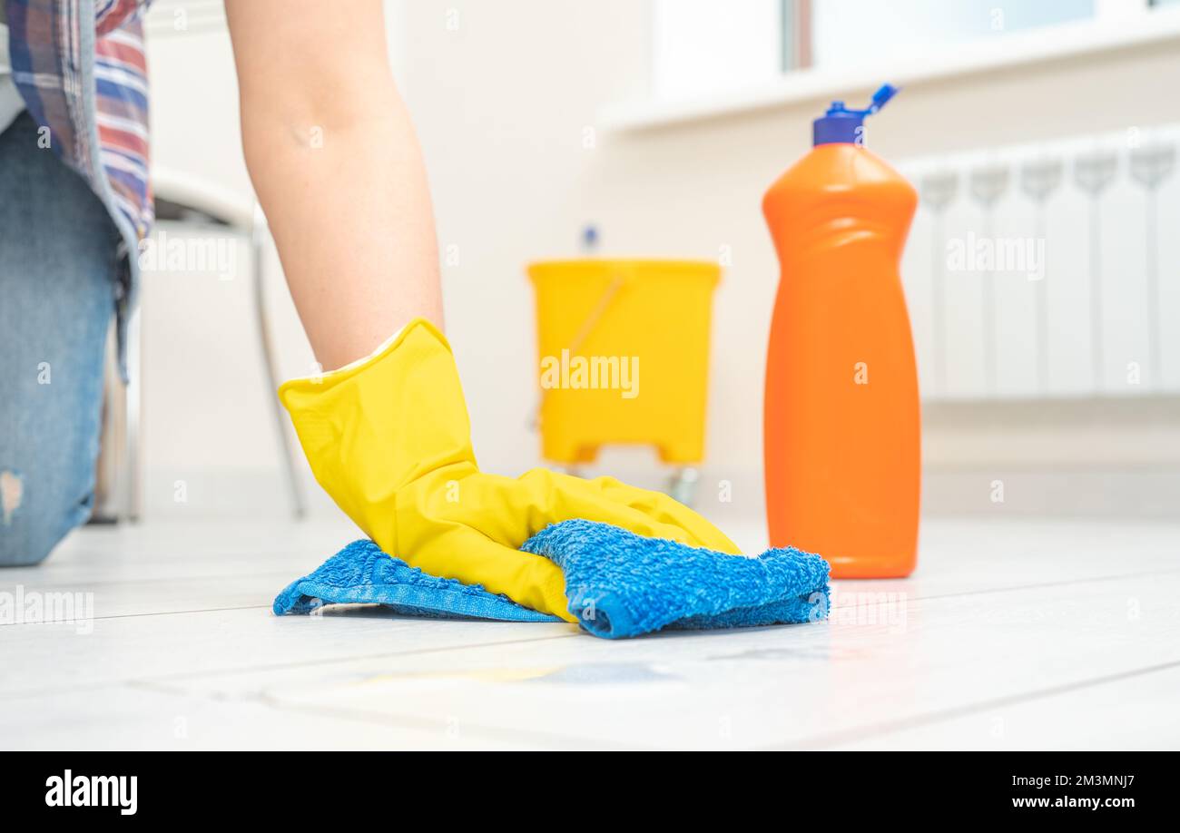 Woman wearing gloves cleaning floor. cleaning and care product for ...