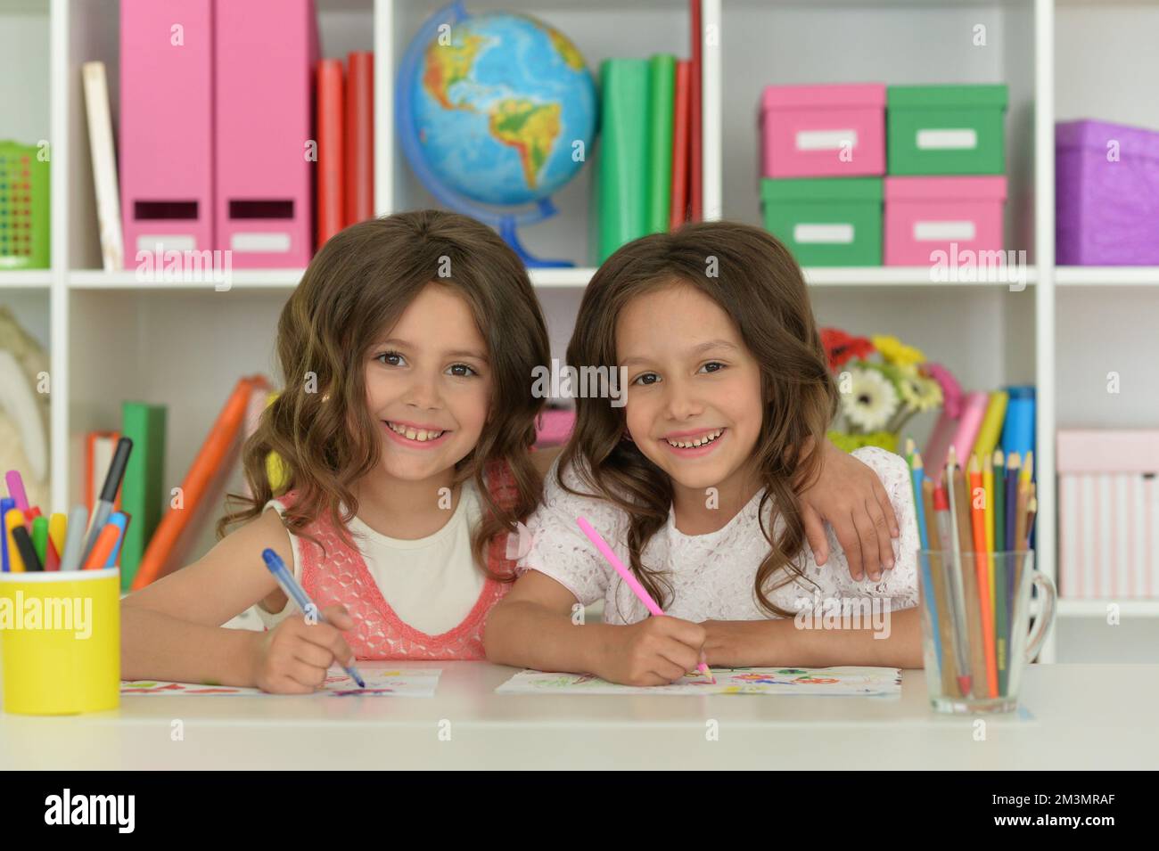 Two cute little girls drawing with pencils Stock Photo - Alamy