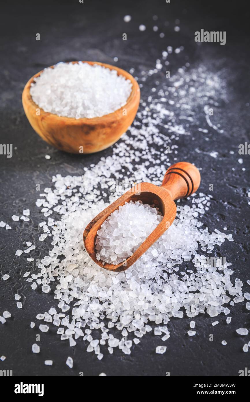 Pure natural sea salt in wooden bowl and wooden spoon on black ...