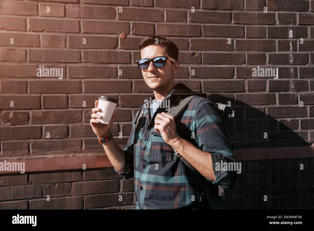 A stylish young man with a mug of takeaway coffee poses against the ...