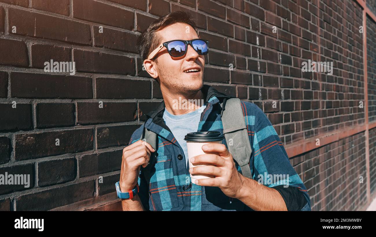 A stylish young man with a mug of takeaway coffee poses against the ...