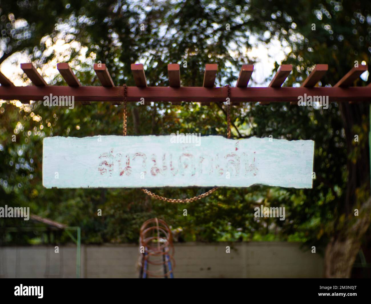 The wooden sign written on it and said "สนามเด็กเล่น" means playground ...