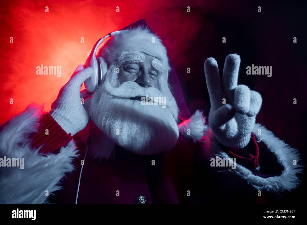 Santa Claus shows 2 fingers listening to music on headphones at a party ...