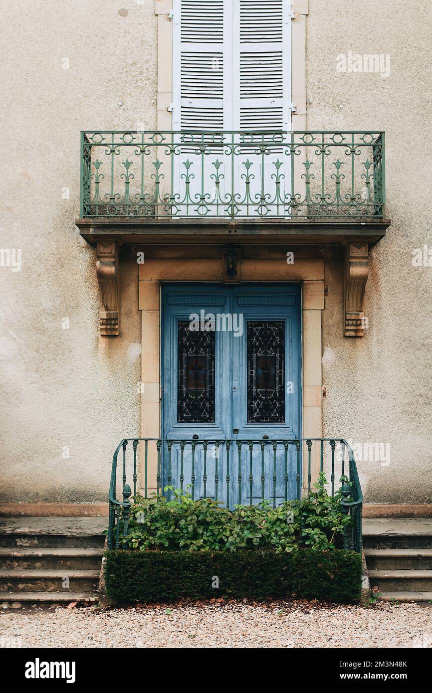 A vertical shot of an old building, blue entrance door and small ...