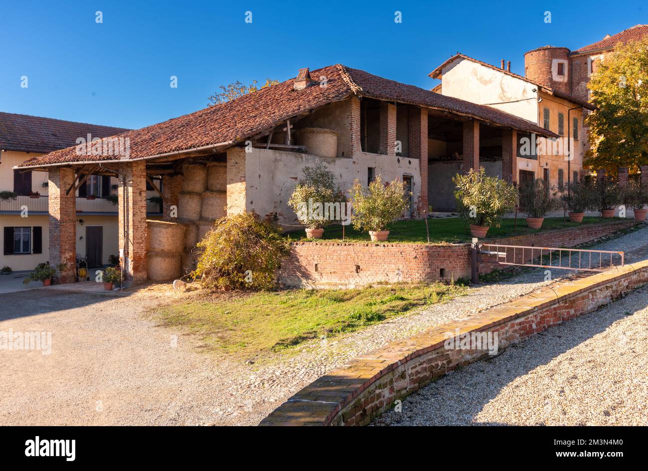 Old barn with round bales of hay under large porch of wooden beams and ...