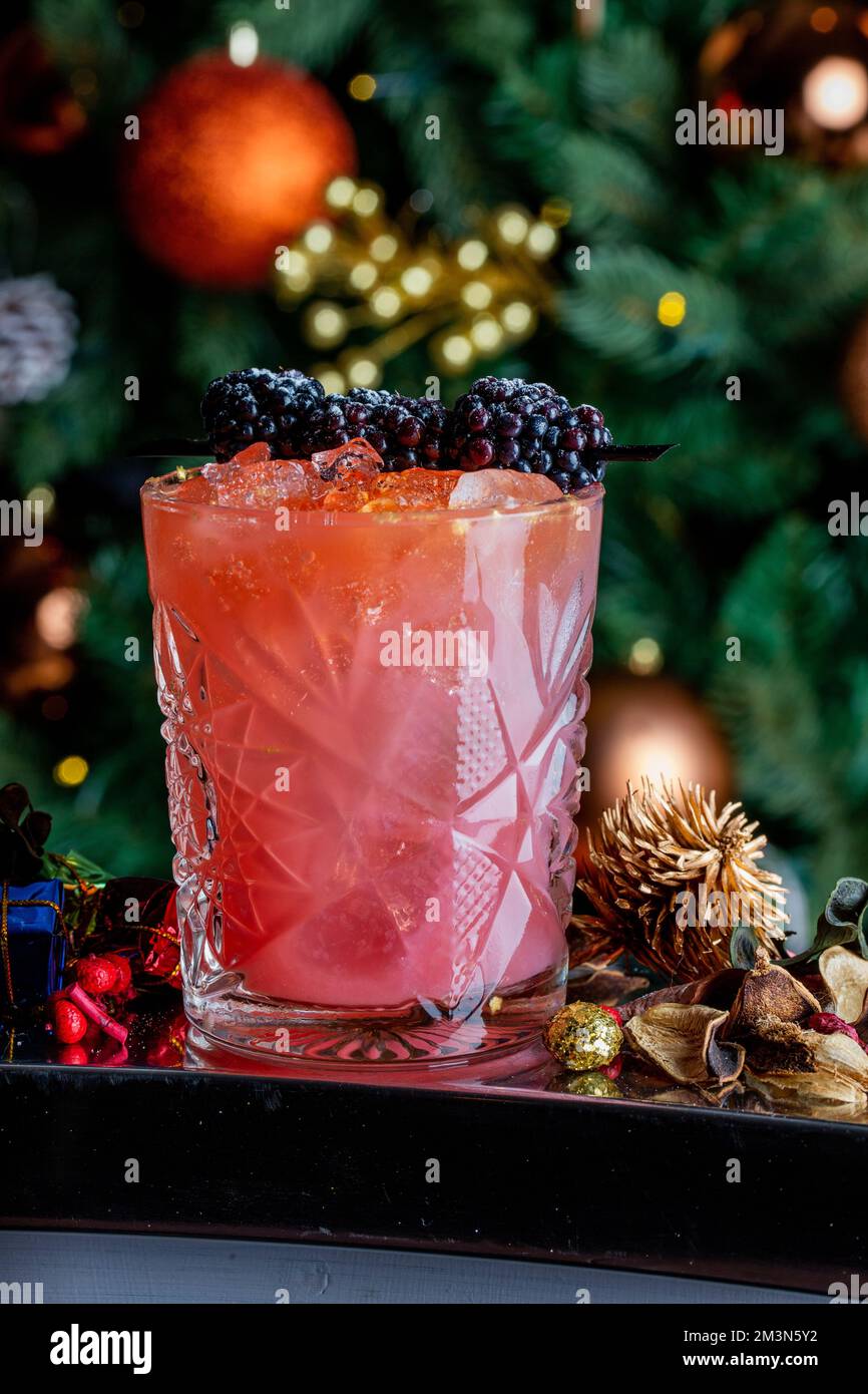 A vertical closeup of a glass of bramble cocktail with blurred ...