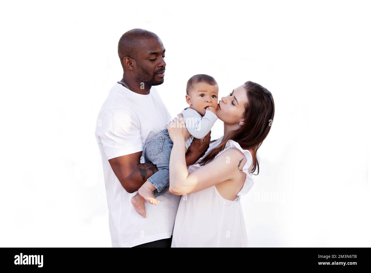 Happy multiracial family. Caucasian Mom and african american dad kiss ...