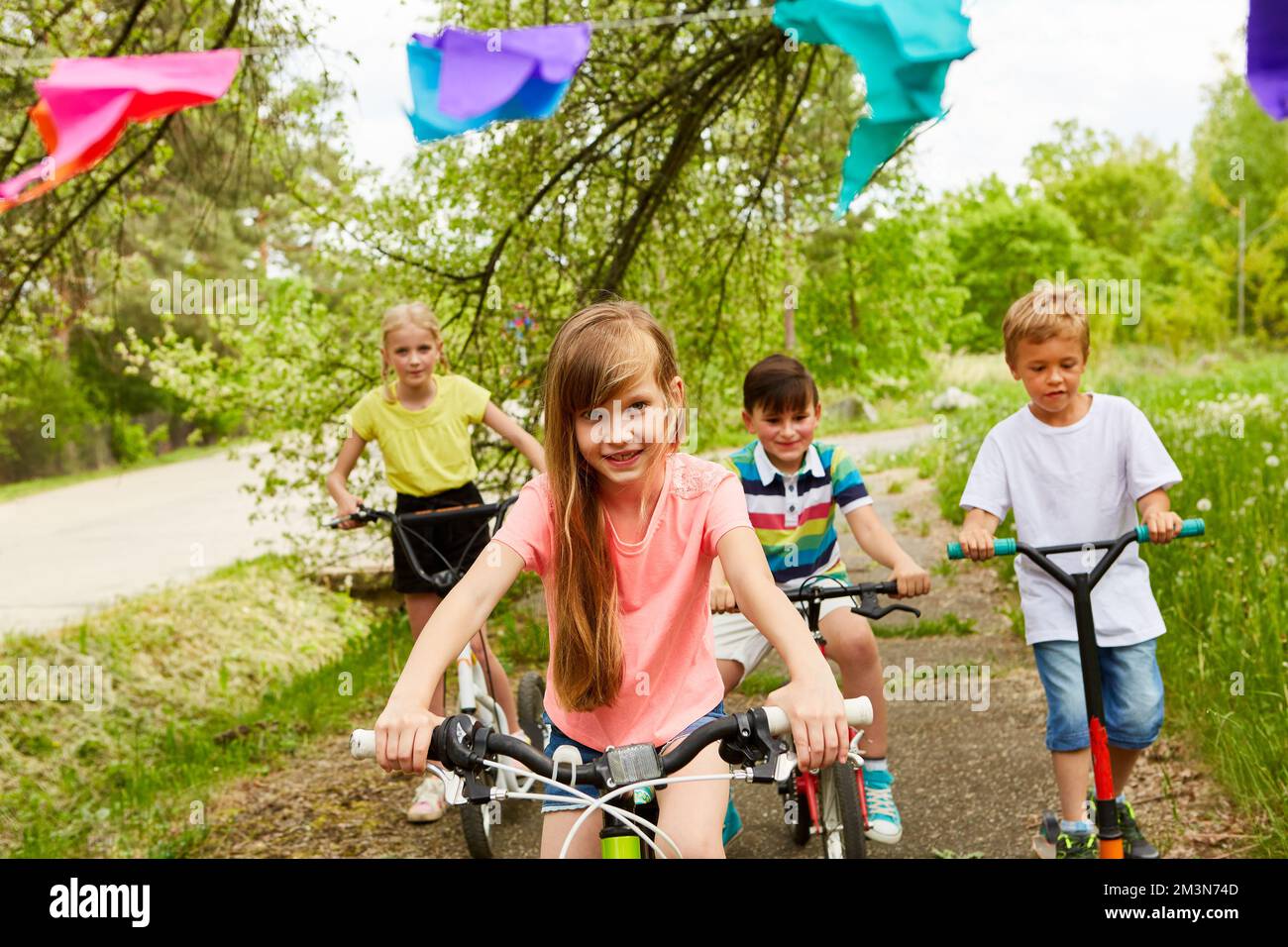 Portrait of smiling girl cycling with male and female friends in ...