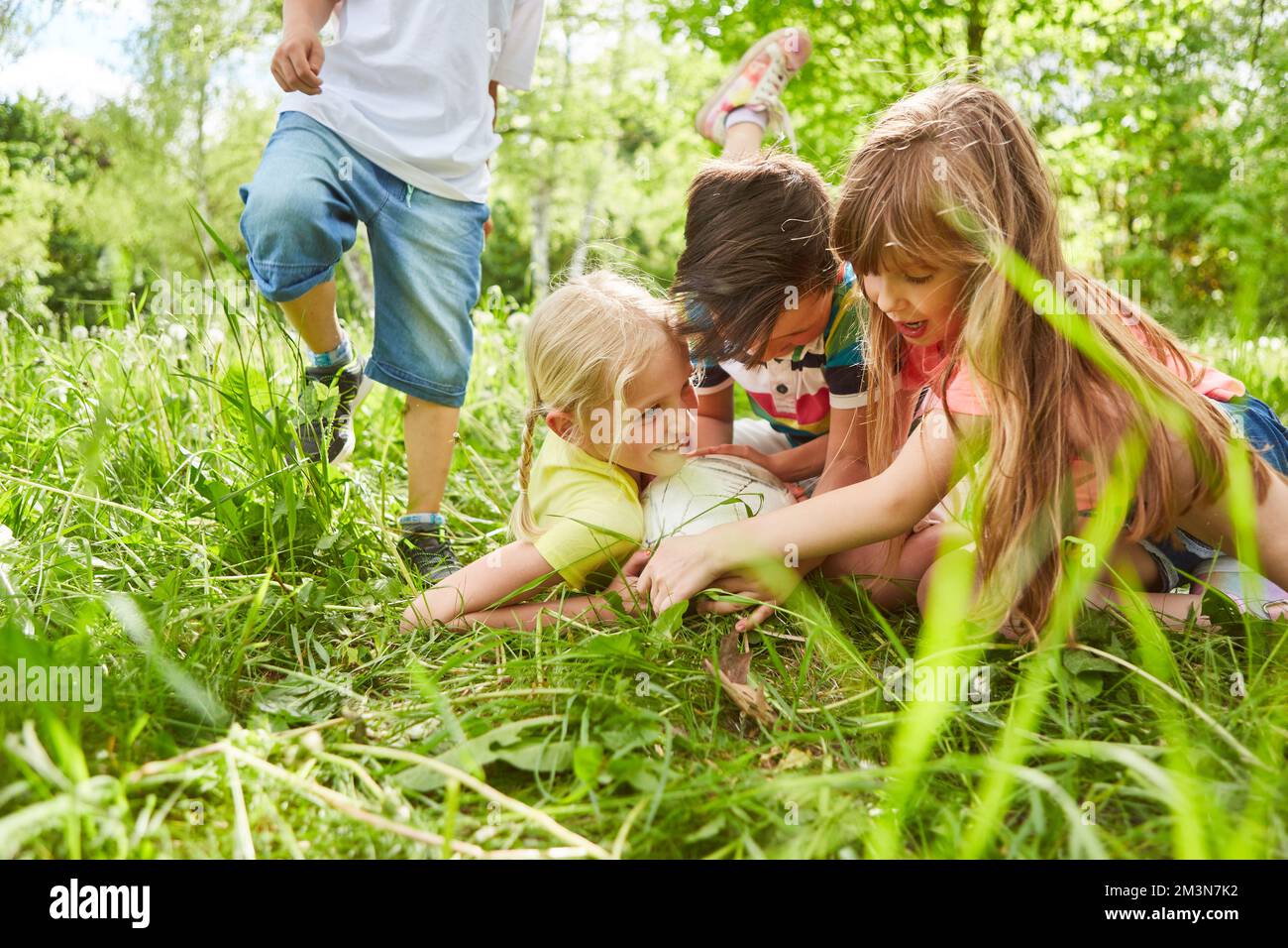 Group of friends playing soccer and fighting over football in grass at ...