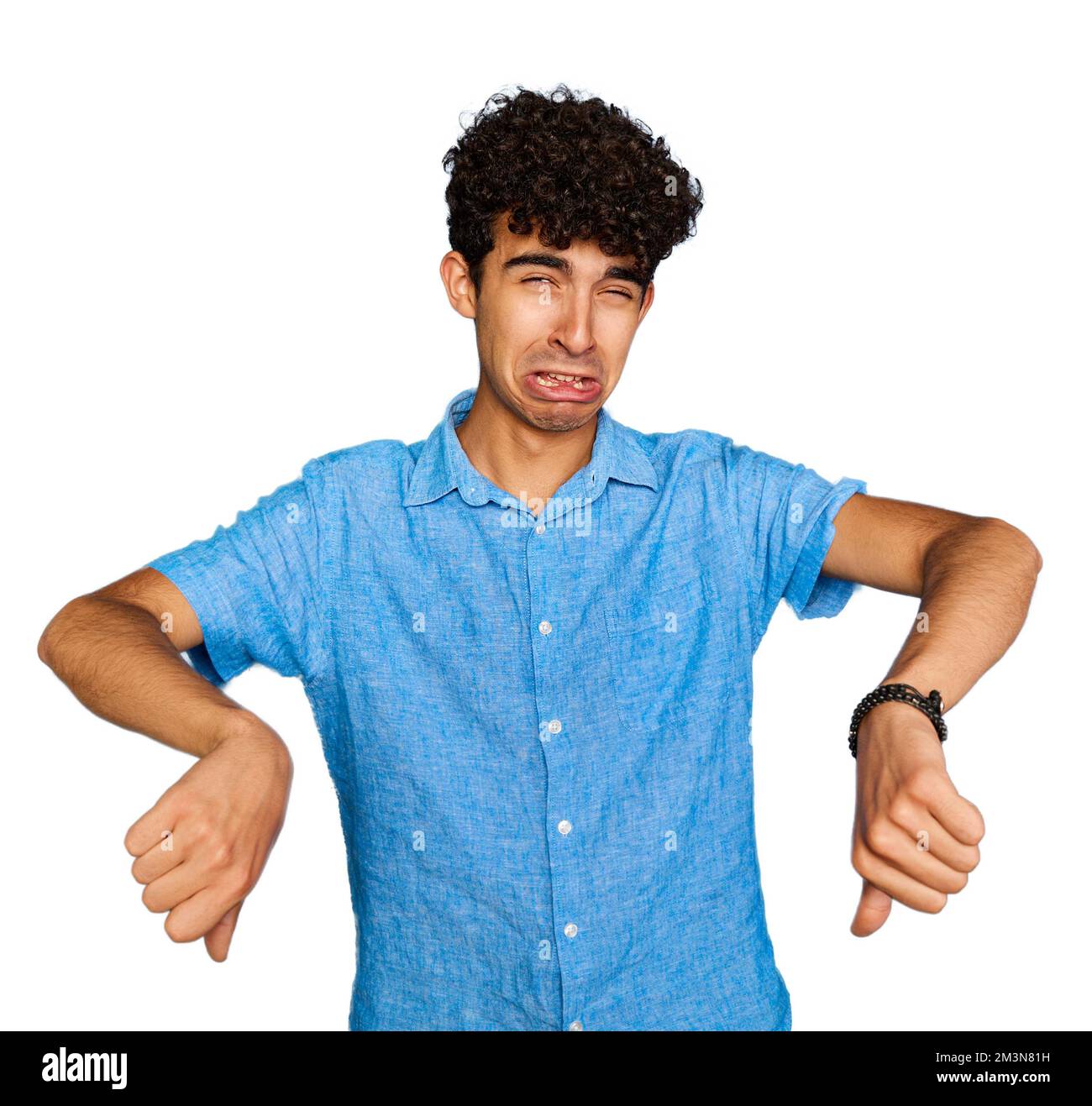 Upset teenage boy with casual clothes and wavy black hair frowning ...